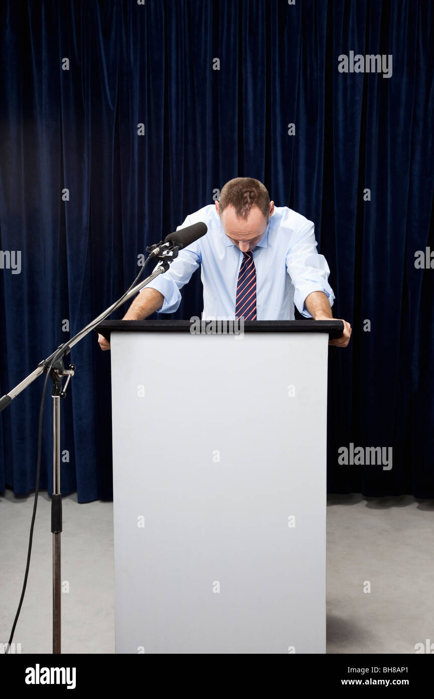 A man looking down behind a lectern Stock Photo - Alamy
