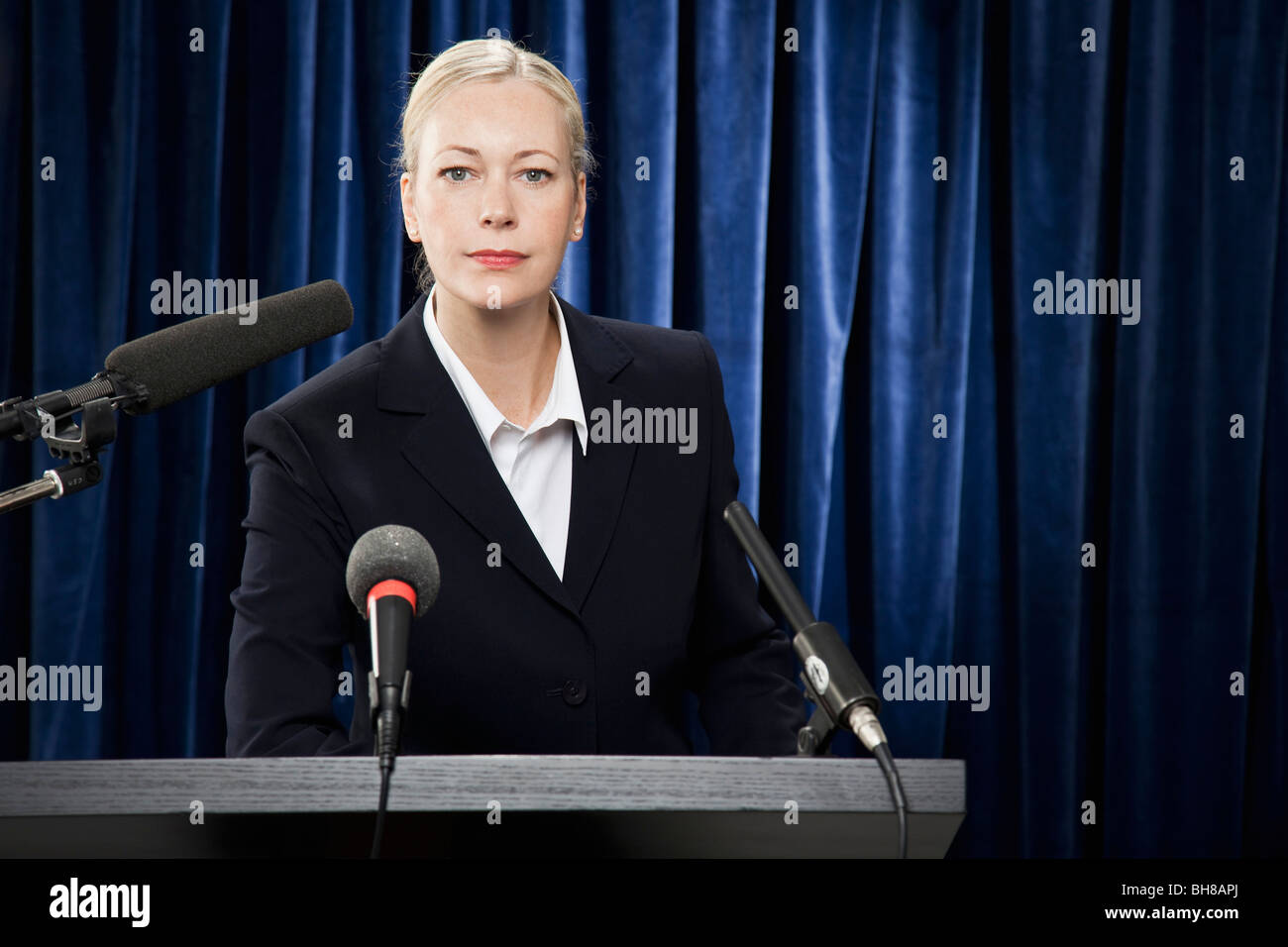 A woman in a suit at a lectern Stock Photo - Alamy