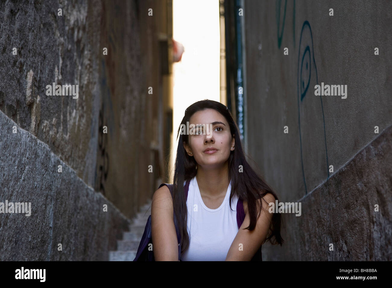 A woman sitting on steps between two buildings, day dreaming Stock ...