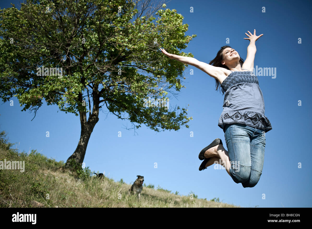 Woman leaping by tree Stock Photo - Alamy