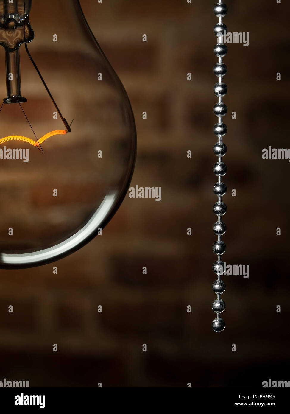 Close up on a transparent light bulb with a pull switch over a brick ...