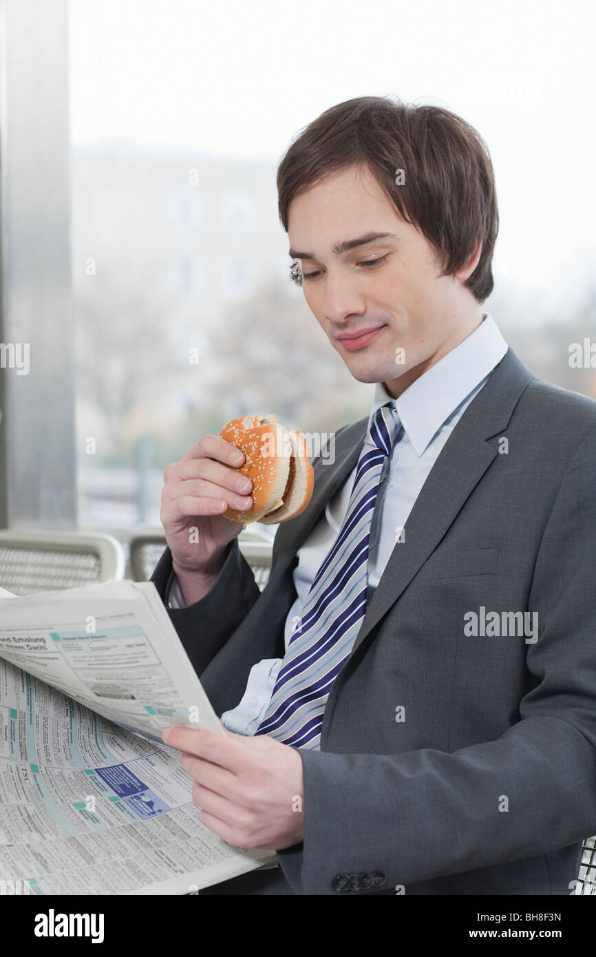 businessman reading whilst eating Stock Photo - Alamy