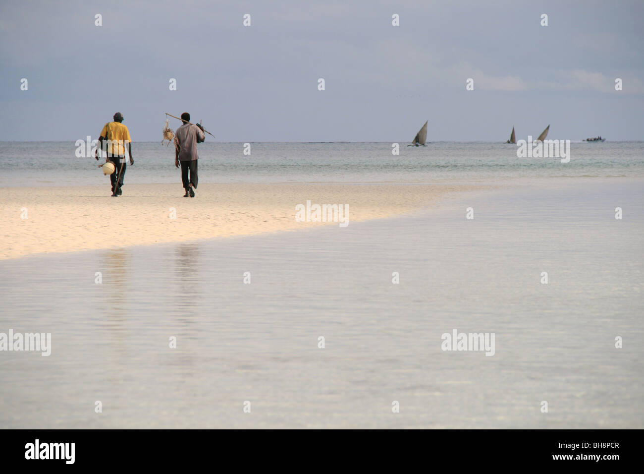 two fishermen walk along the sand spit to deeper water Stock Photo - Alamy