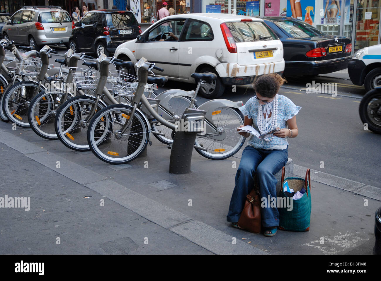 A woman reading beside a row of Velibs (a public rental bicycle ...
