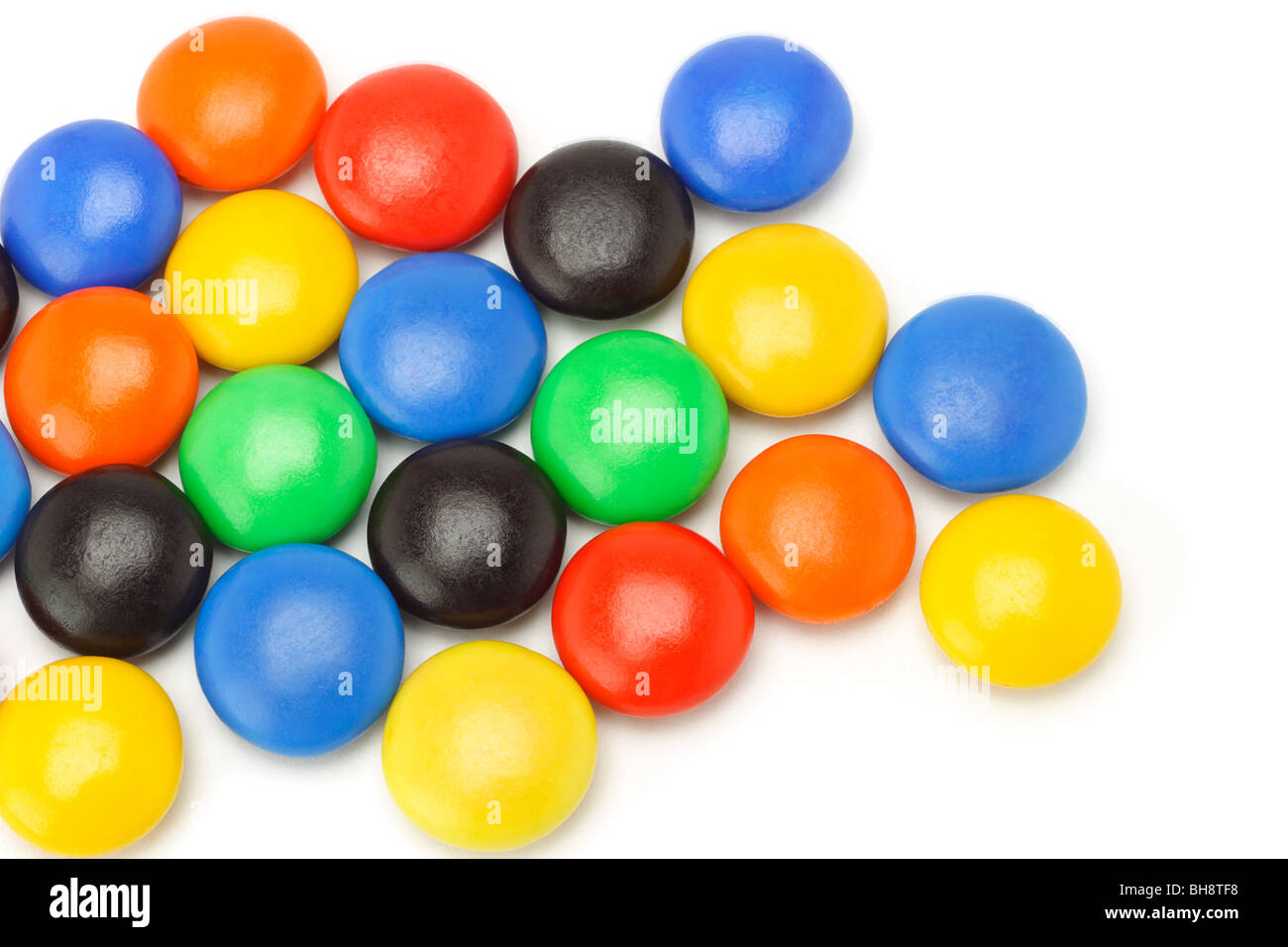 Colorful chocolate button candies spreaded randomly on white background ...