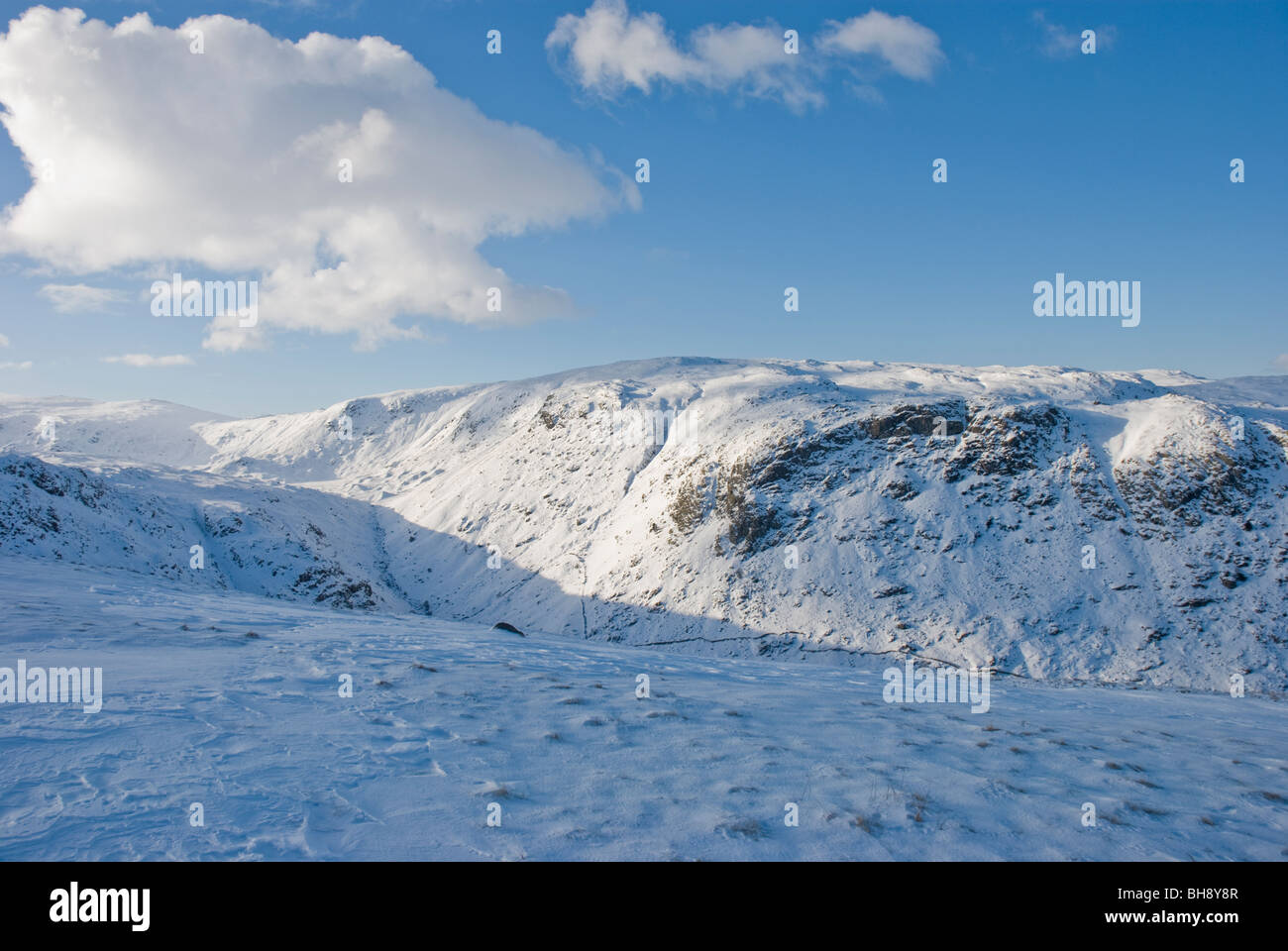 The Cumbrian Lake District fells covered in snow with blue sky and ...
