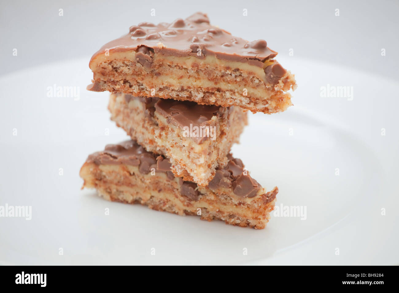 Stack of triangular chocolate-covered caramel and biscuit slices on a ...