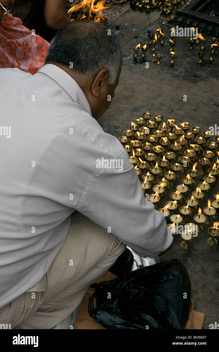 buddhist devotee lighting butter lamps at the swayambunath stupa shrine ...