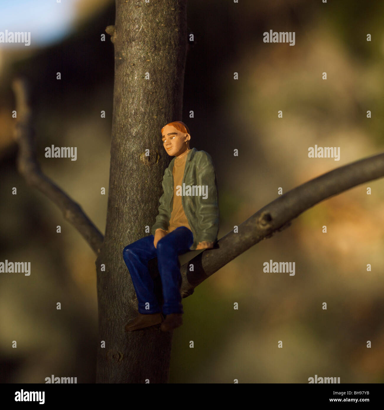 Man, figurine, sitting on a branch of tree Stock Photo - Alamy