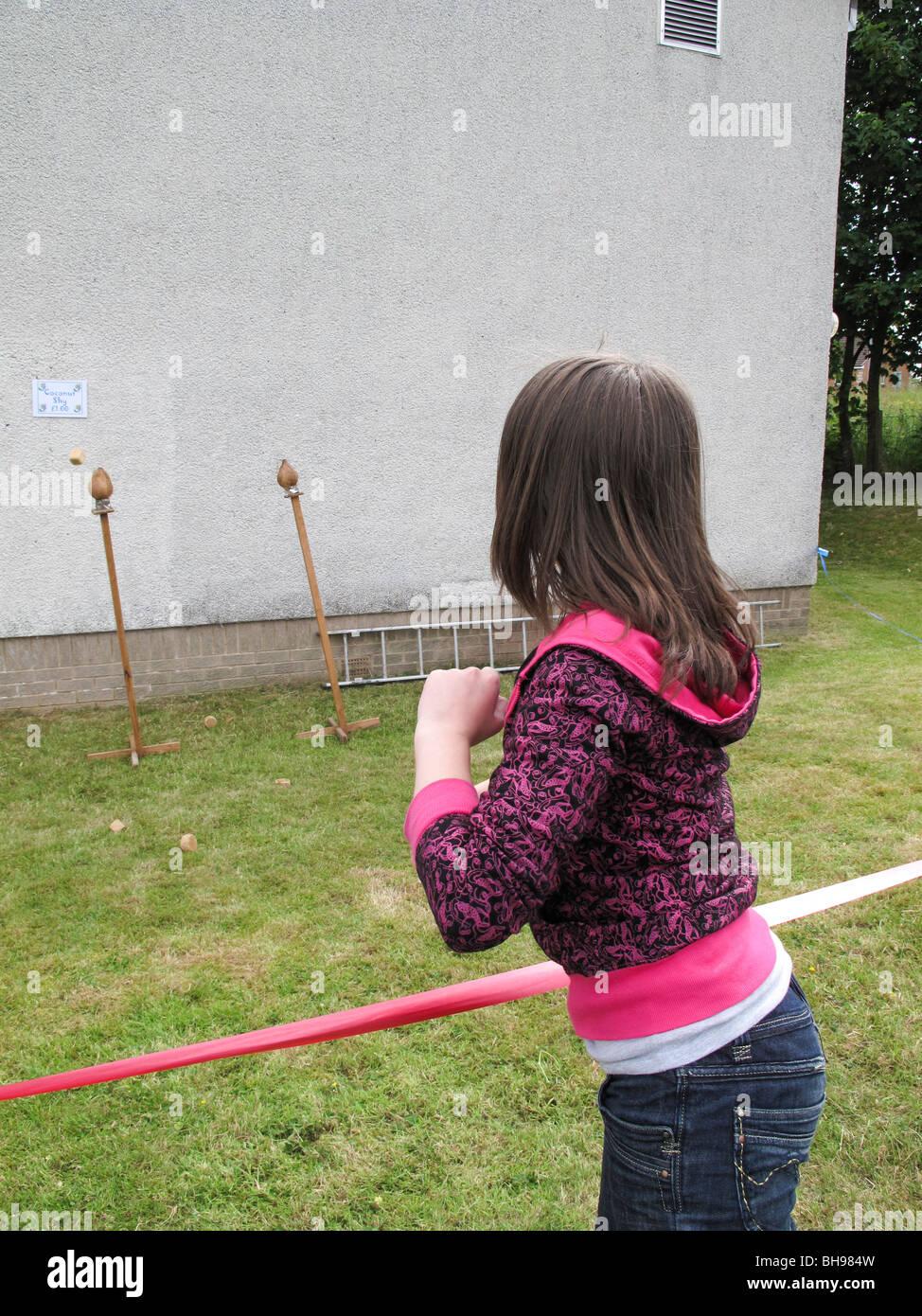 Girl playing at coconut shy Stock Photo - Alamy