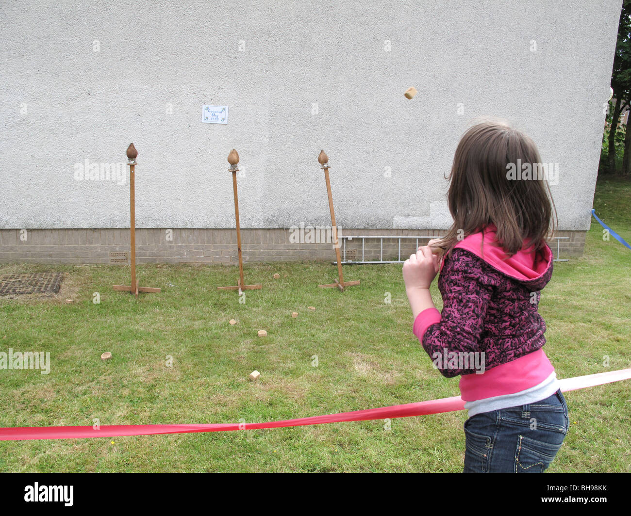 Girl playing at coconut shy Stock Photo - Alamy