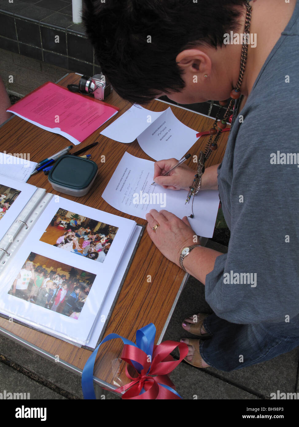 Woman signing form on table Stock Photo - Alamy
