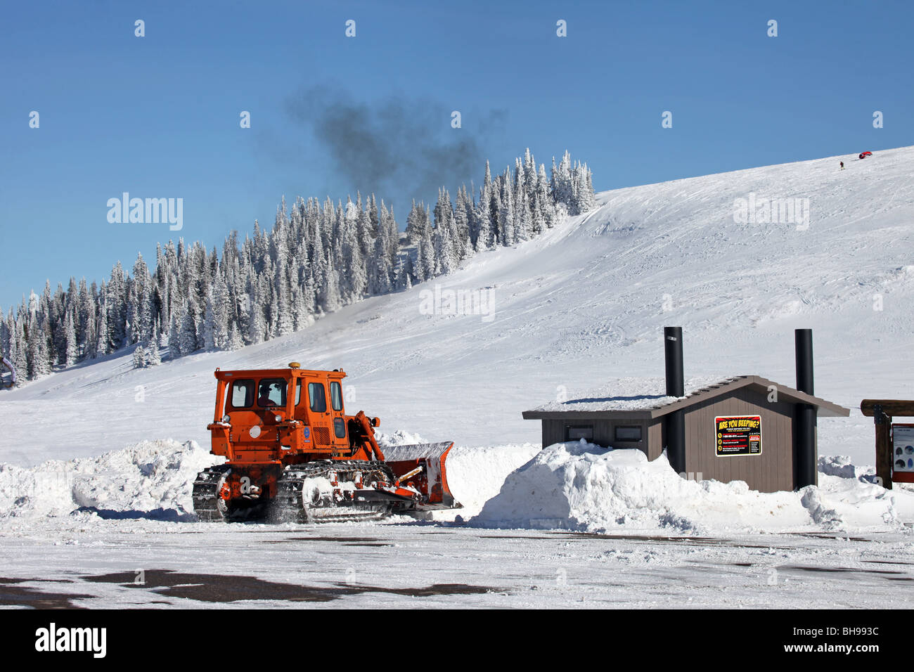 Caterpillar bulldozer push snow off mountain top parking road central ...