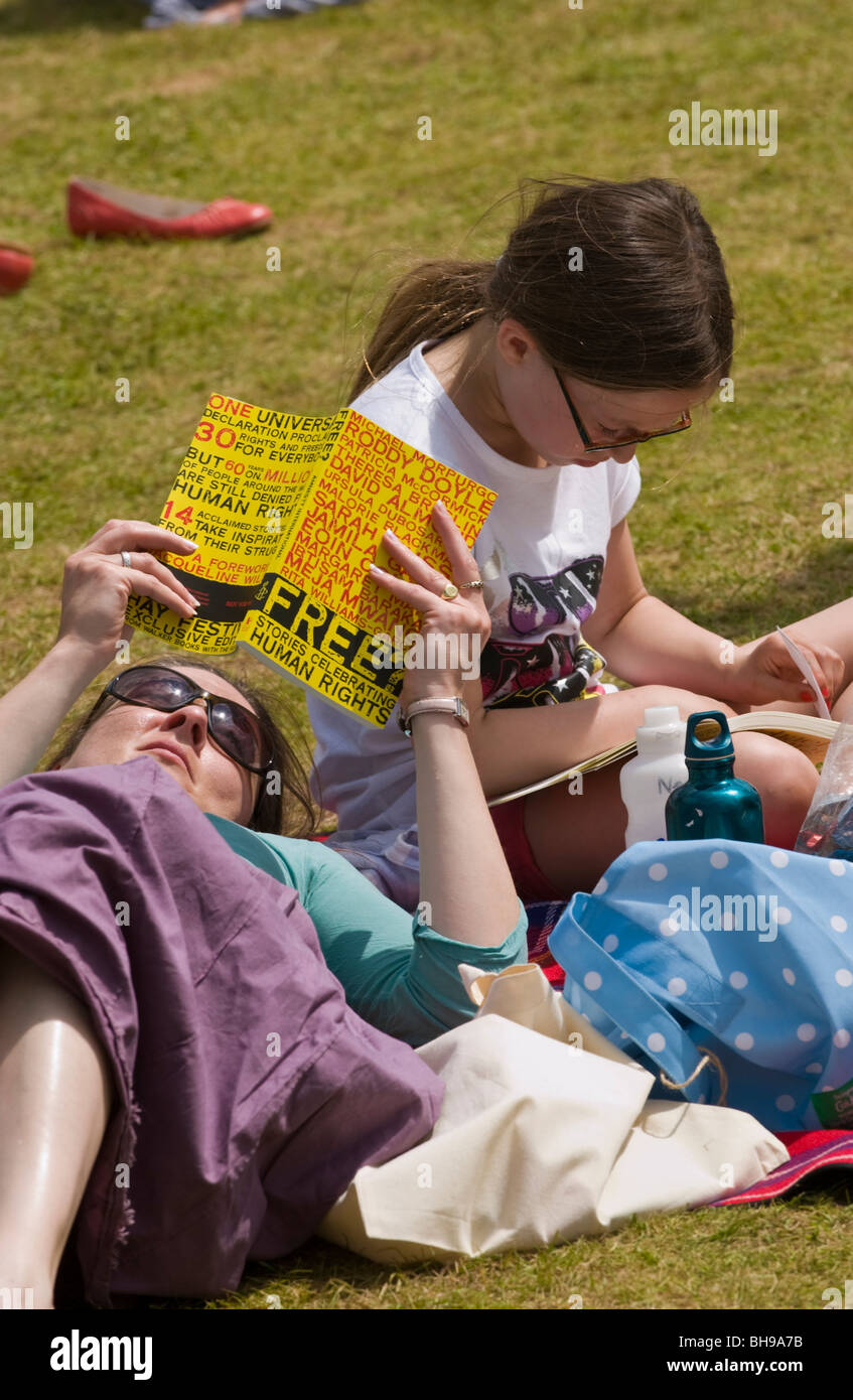 Woman and child reading books lying on grass relaxing outside in the ...