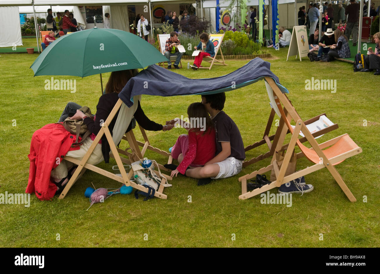 Family group relaxing and chilling outside under a homemade shelter at ...