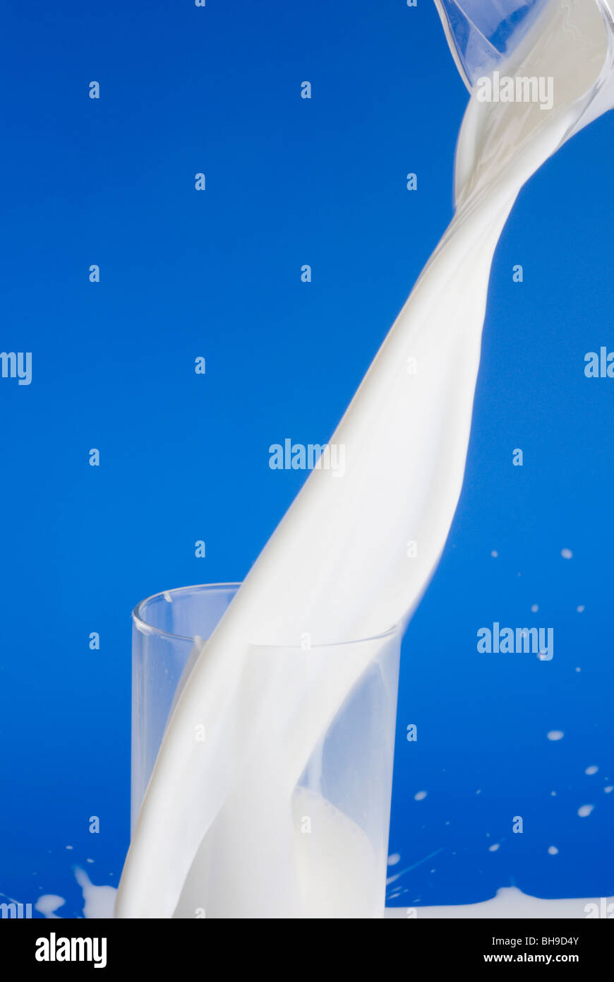 Stream of milk being poured in a glass on blue background Stock Photo ...