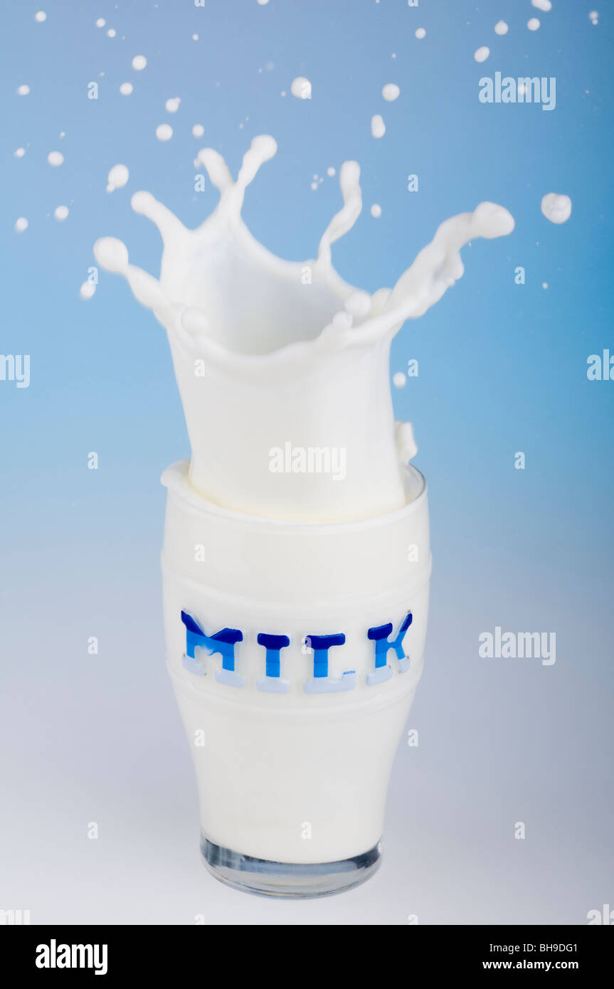 Milk being splashed out from a glass on blue Stock Photo - Alamy