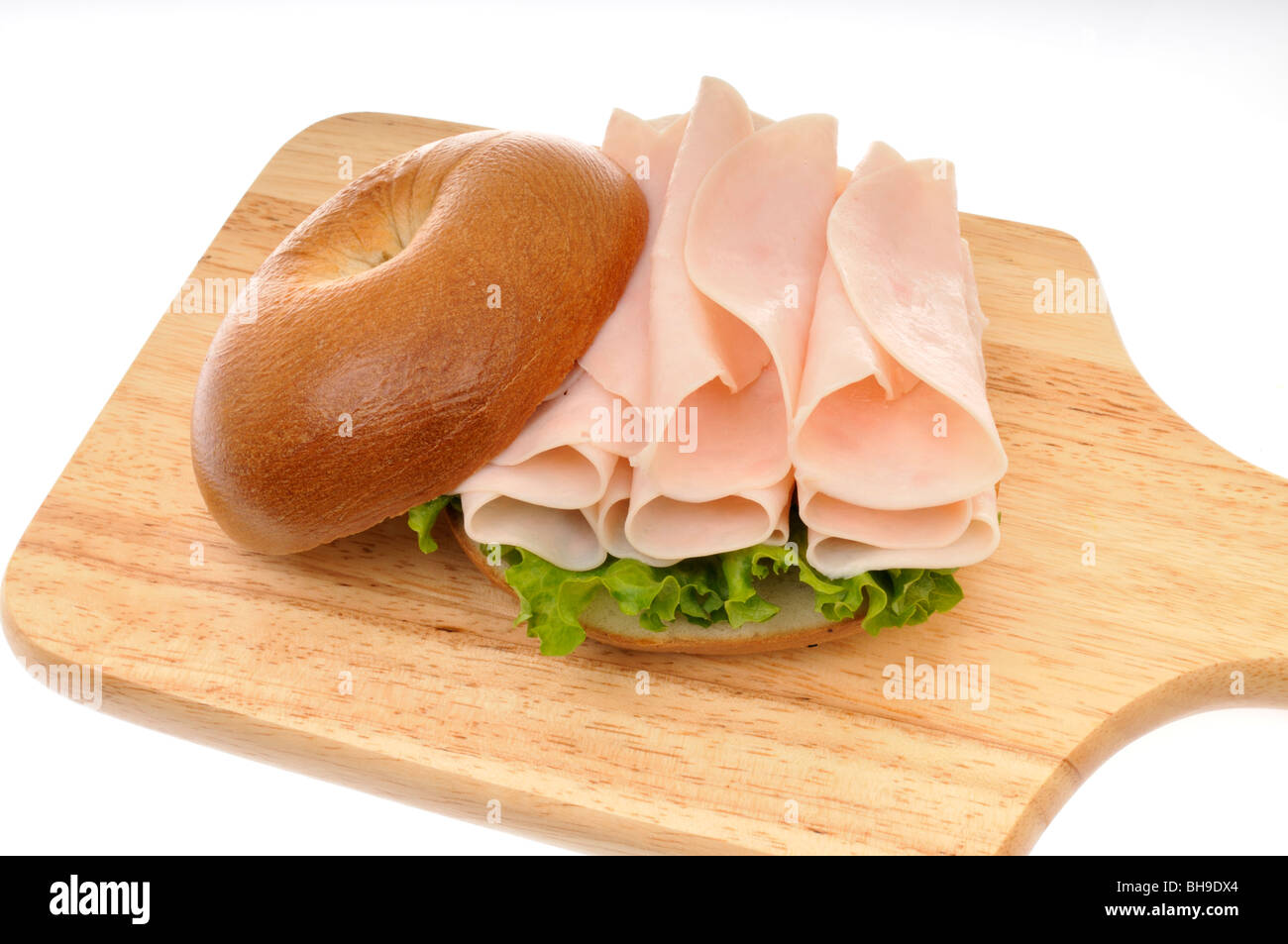 Rolled deli turkey sandwich with lettuce and tomato on a bagel on a ...