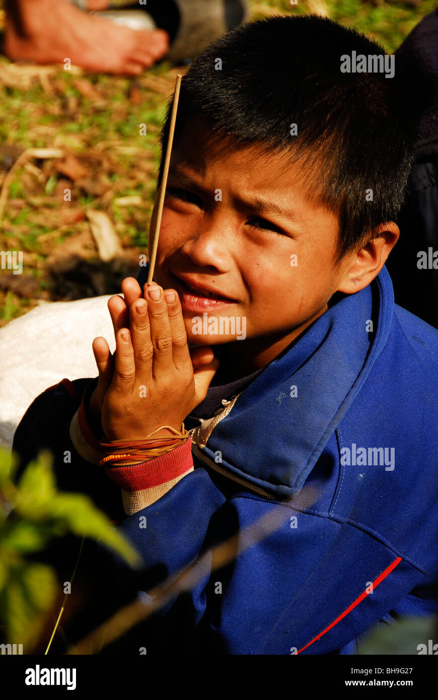 Karen refugee boy with joss stick in his palms at karen funeral at Thai ...