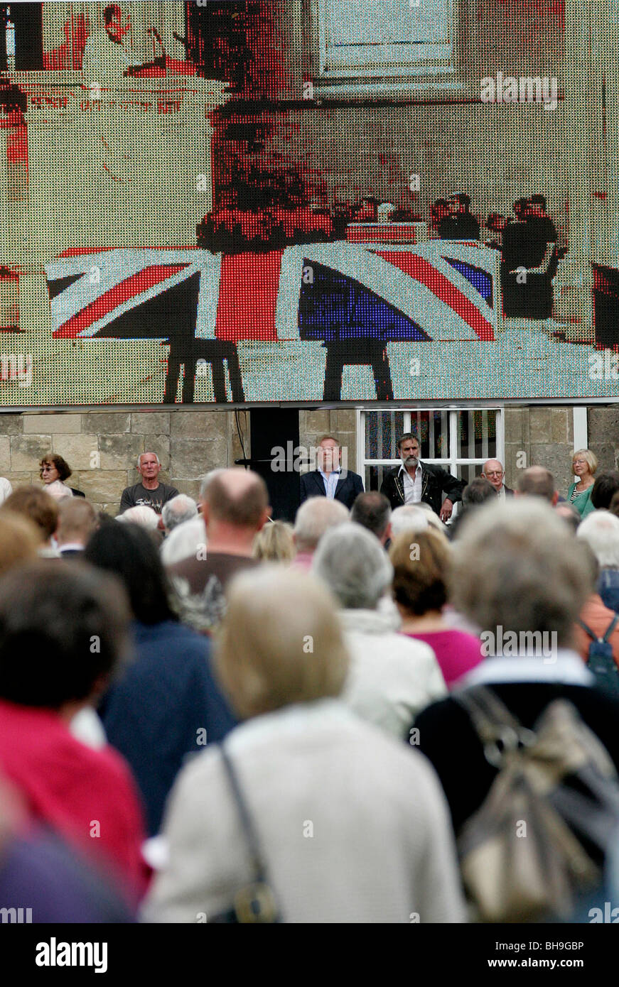 Mourners watch the funeral of war veteran Harry Patch on a big screen ...