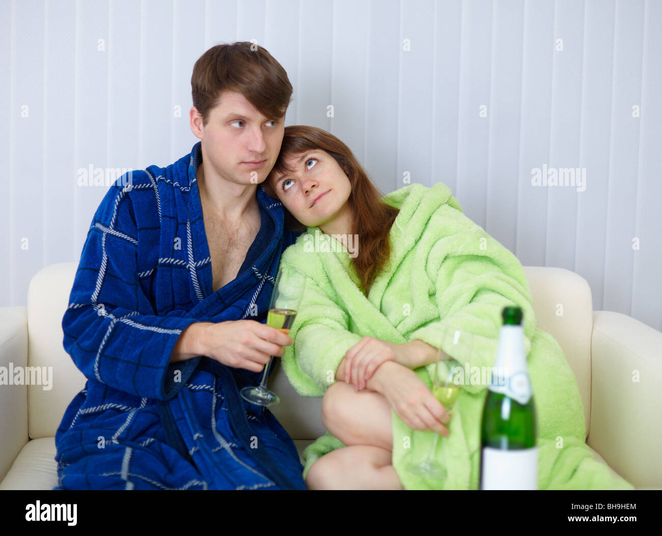 Young people sit at home on the couch in dressing gowns with fizz Stock ...
