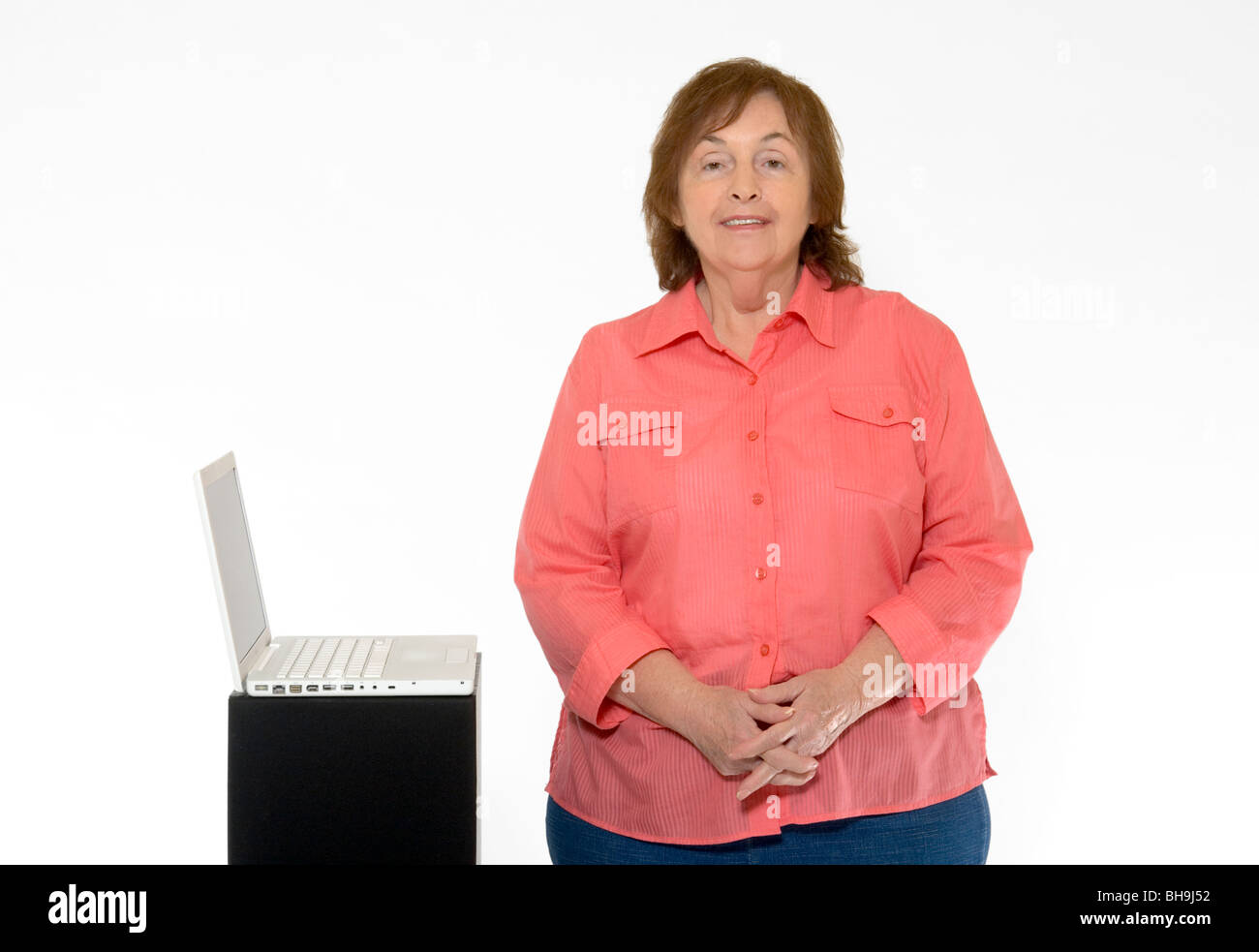 A senior retired elderly woman stands next to a laptop computer Stock ...