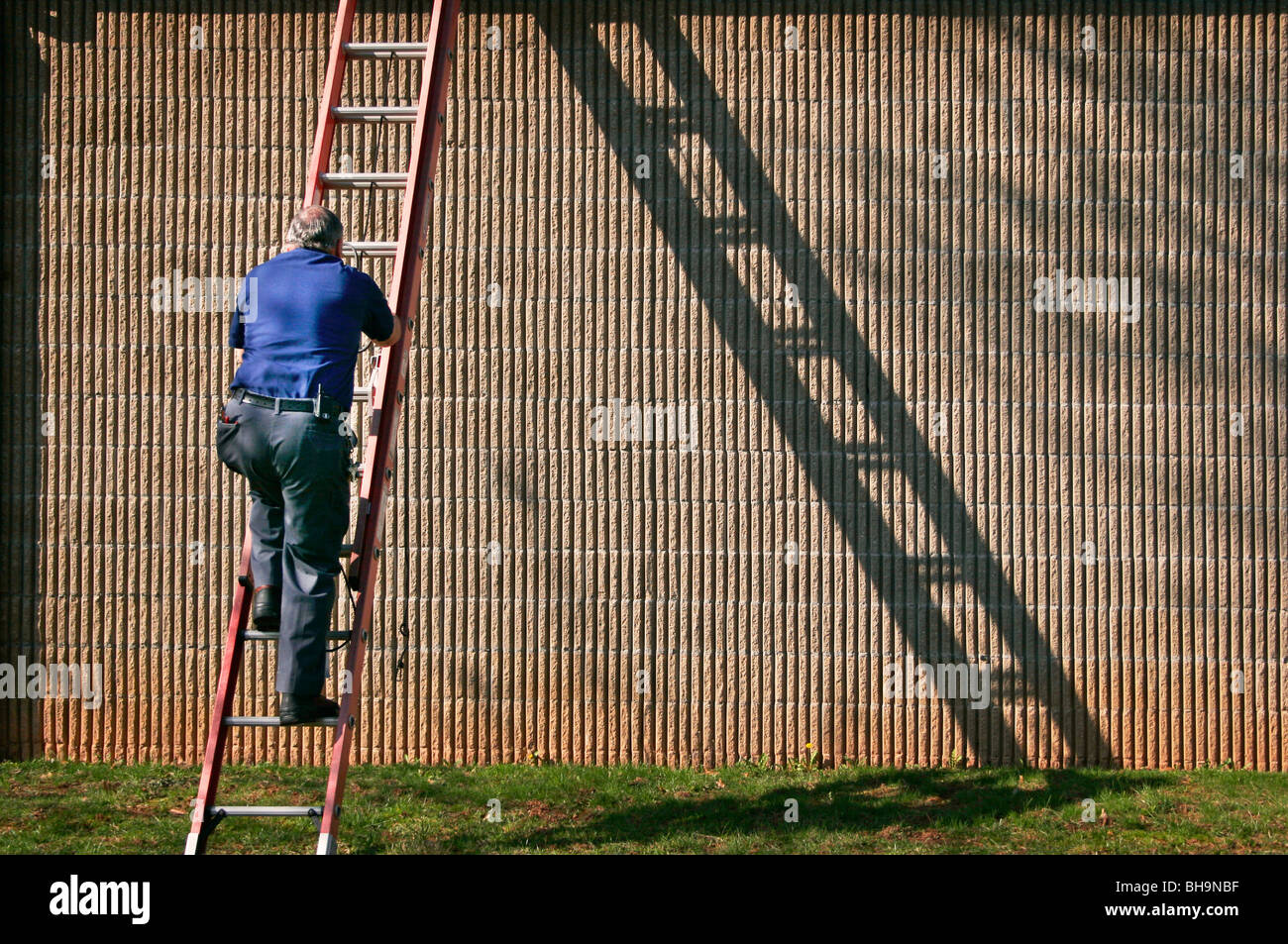 man climbing ladder to do building repair on building day time Stock ...