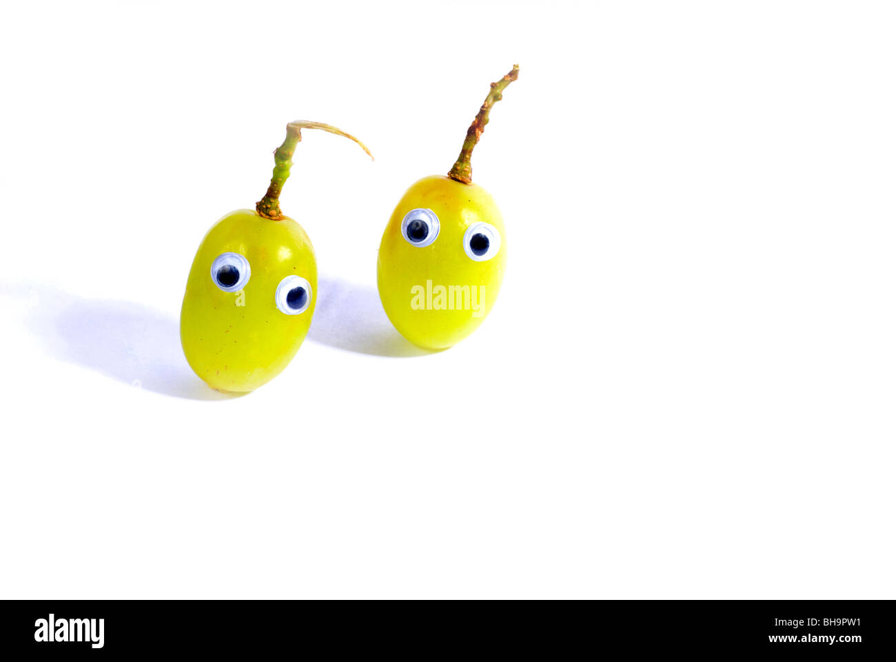A cut out image of two grapes with cartoon like eyes attached to them ...