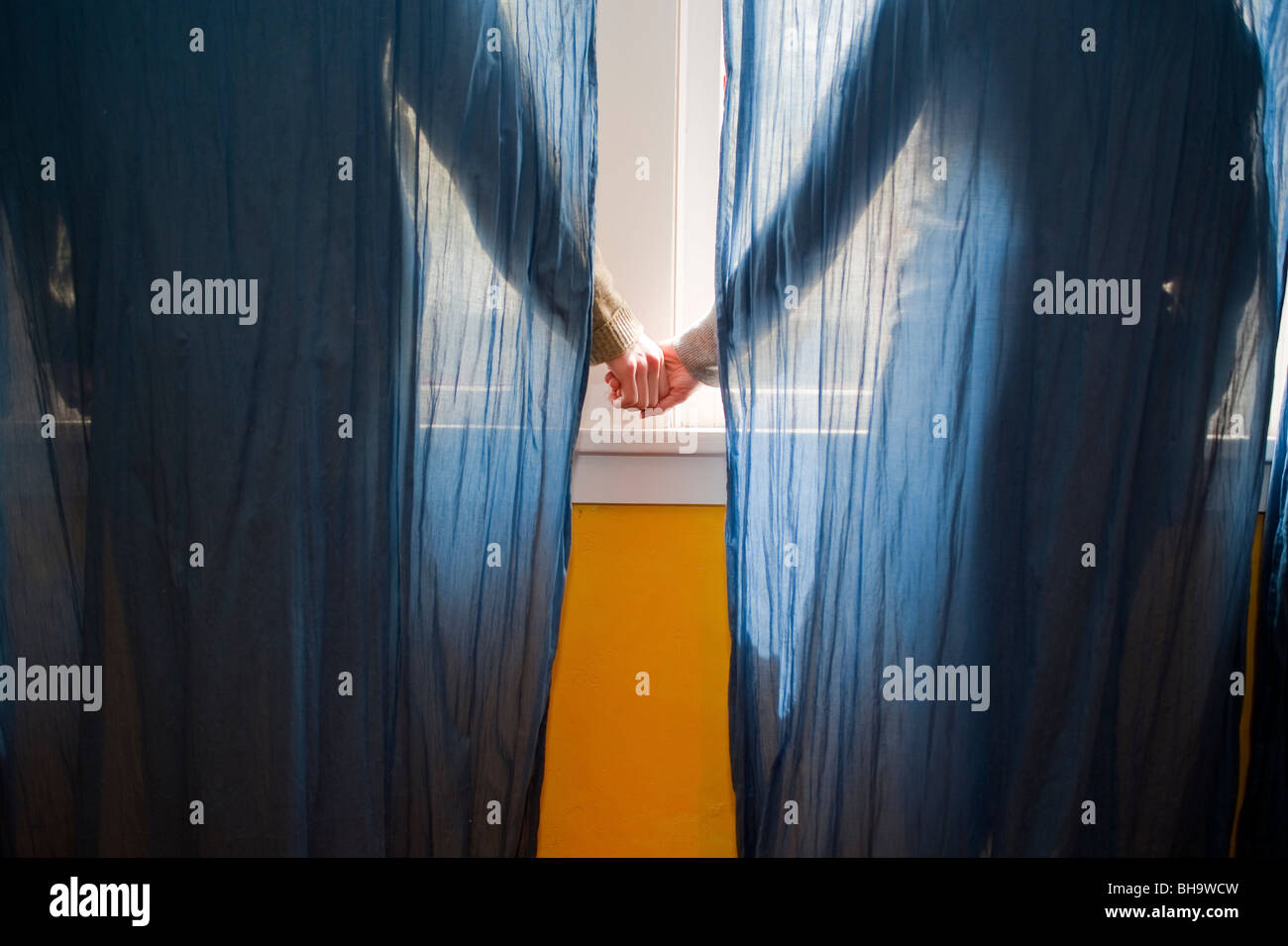 Young couple holding hands behind blue curtains Stock Photo - Alamy