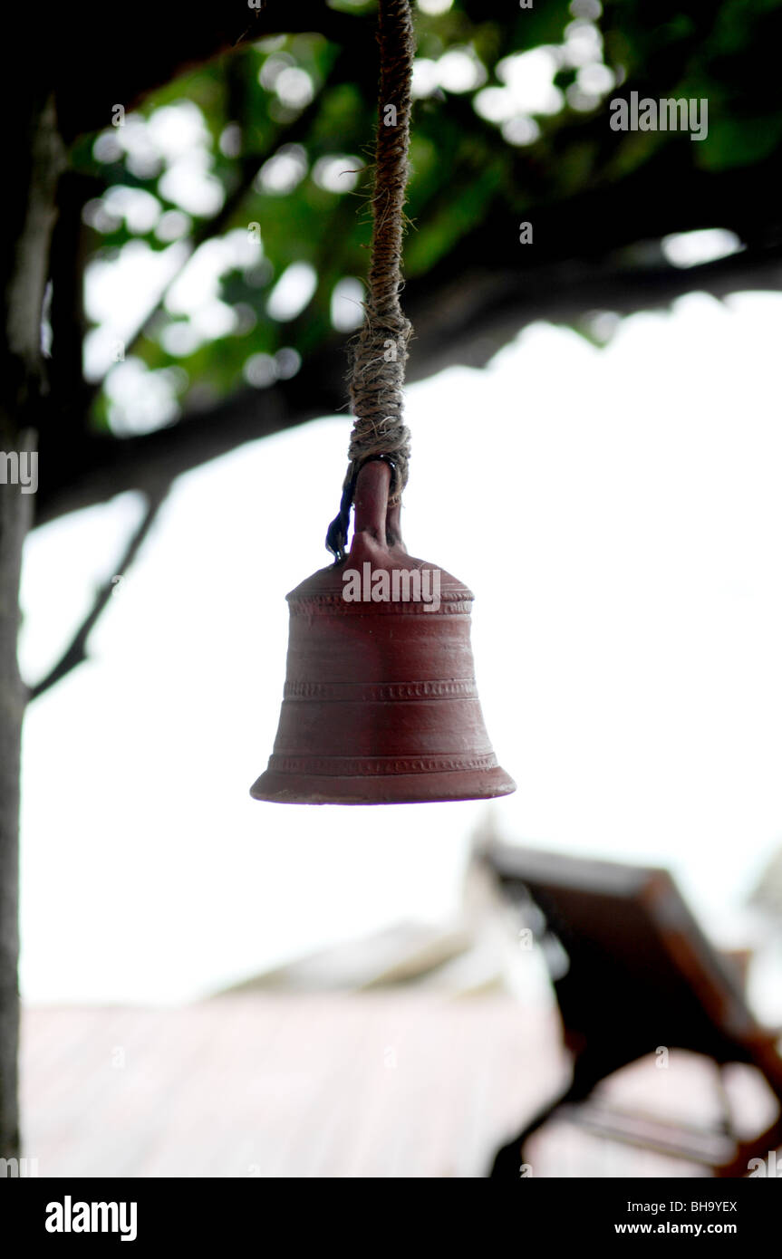Bell hanging from a tree with deck chairs as background Stock Photo - Alamy