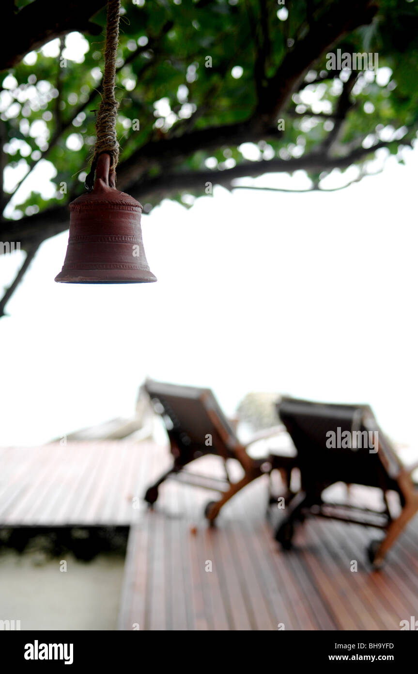 Bell hanging from a tree with deck chairs as background Stock Photo - Alamy