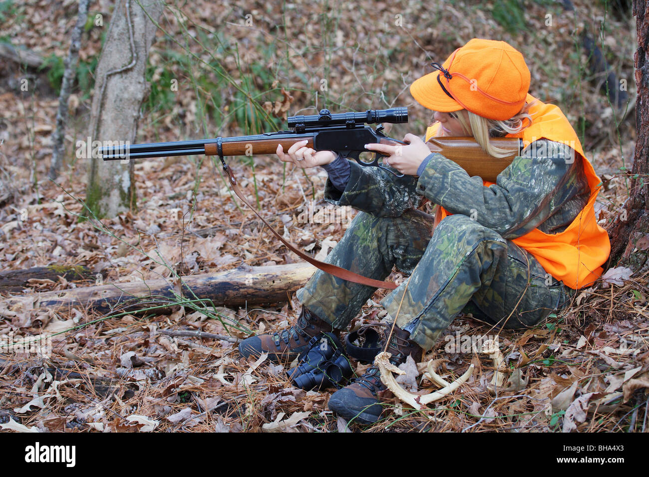 CLOSE UP YOUNG WOMAN 21 Y.O. FEMALE DEER HUNTER SITTING AGAINST TREE IN ...