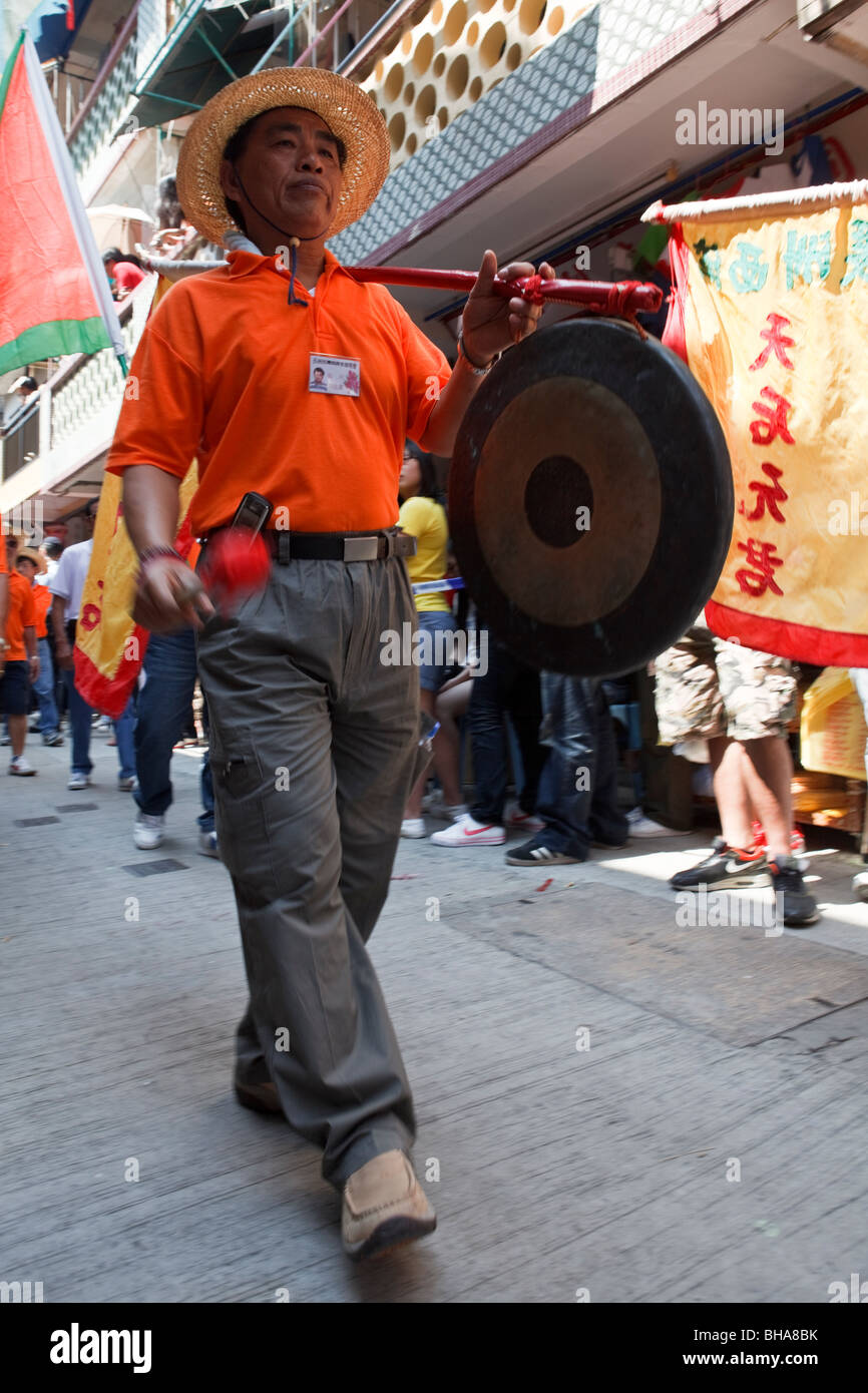 A man sounding a gong in the procession at the Cheung Chau Bun Festival ...