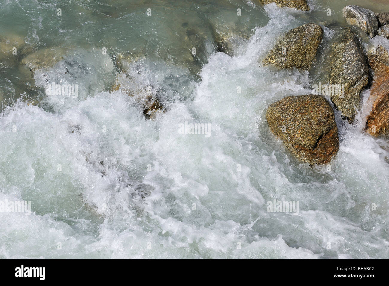 Glacial water flowing fast over boulders in alpine mountain stream ...