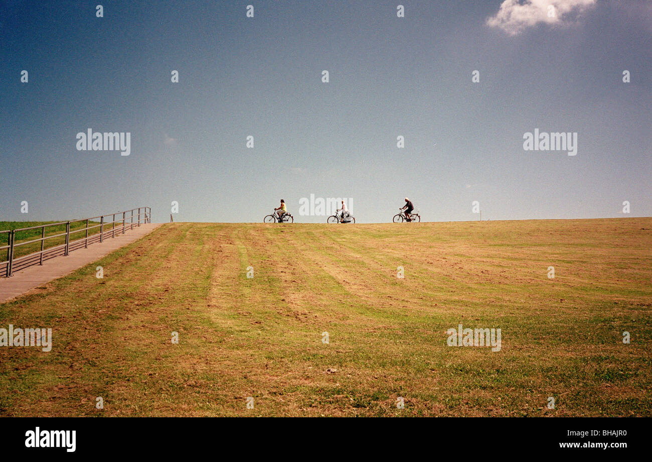 Three riders riding their bikes against the skyline in northern Germany ...