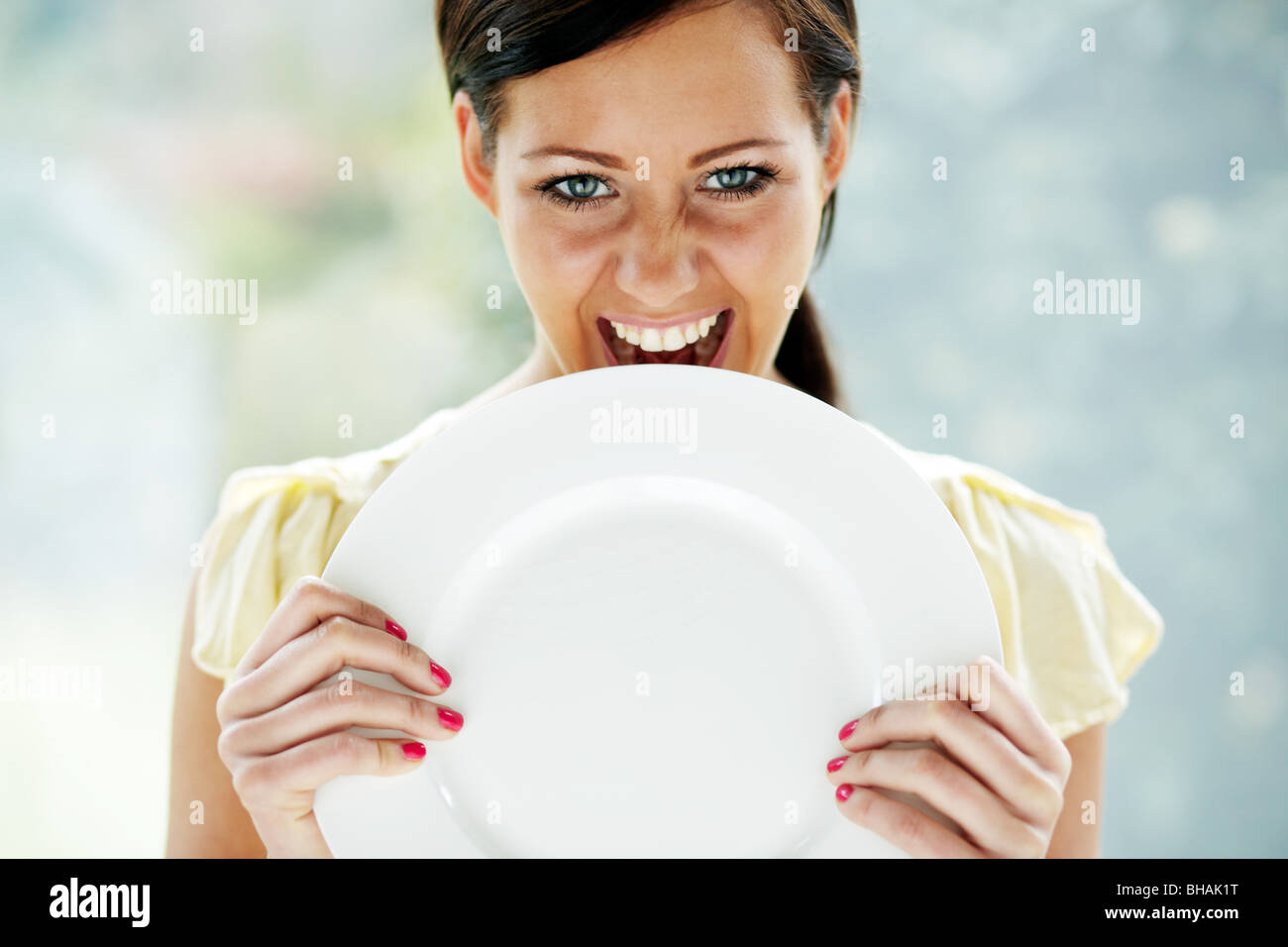 Girl biting plate Stock Photo - Alamy