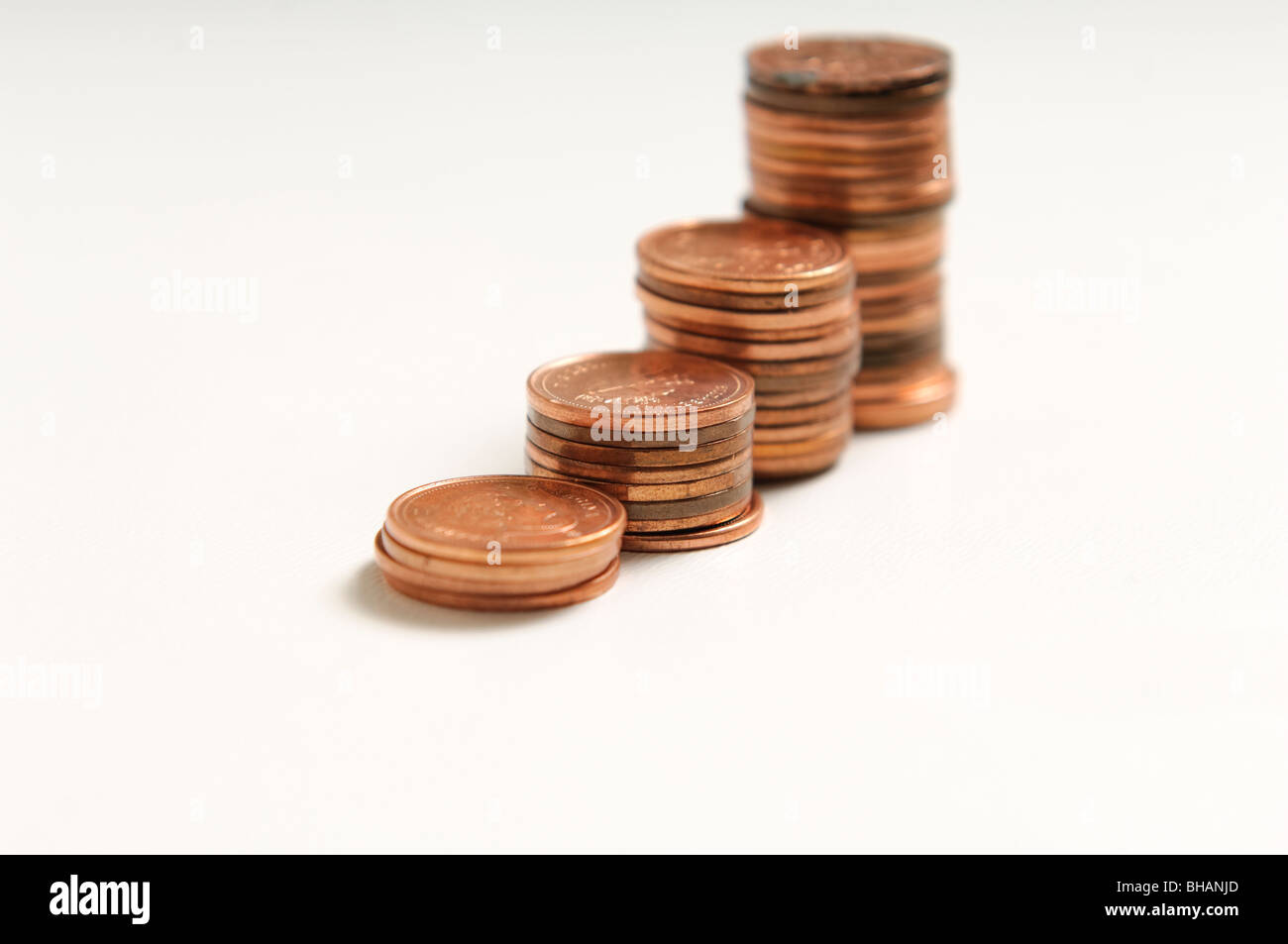 4 stacks of coins, each stack increasing in size. Shot on a white ...