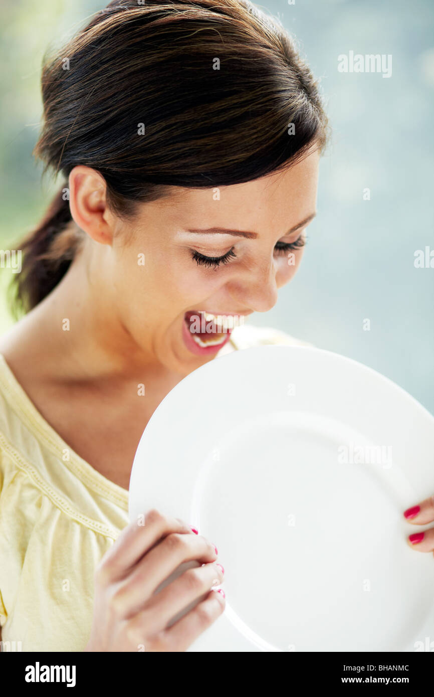 Girl biting plate Stock Photo - Alamy