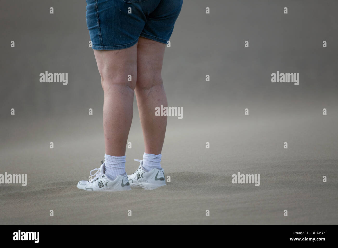 Wind blows sand around the feet of a visitor in Great Sand Dunes ...