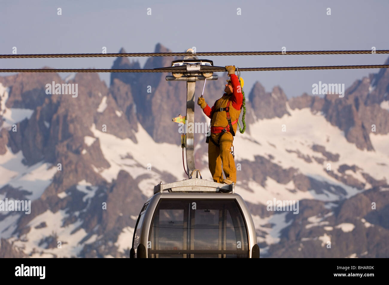 Ski resort workers working on top of a gondola with mountains and snow ...