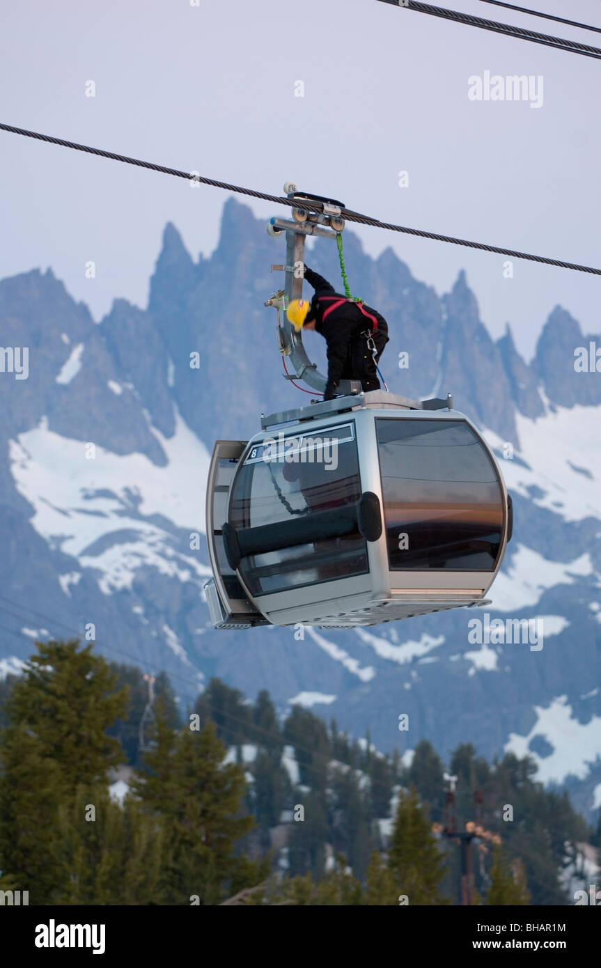 Ski resort workers working on top of a gondola with mountains and snow ...