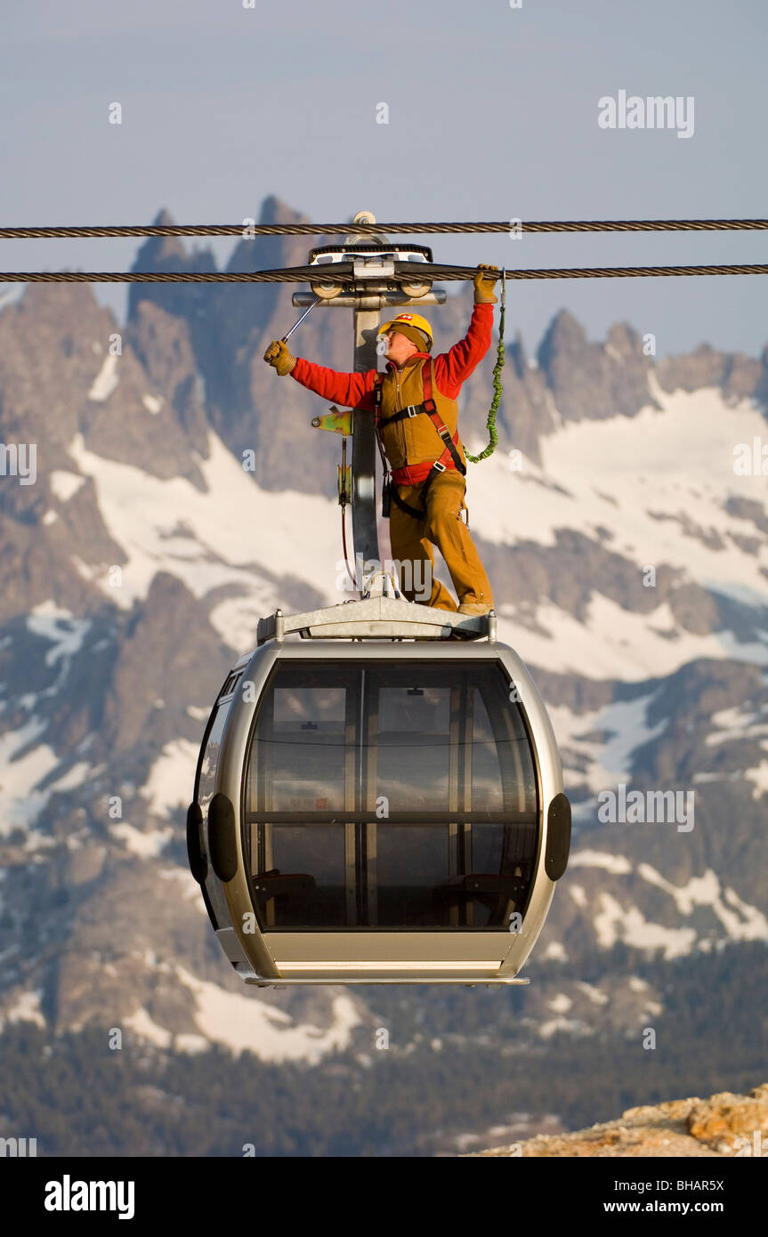 Ski resort workers working on top of a gondola with mountains and snow ...
