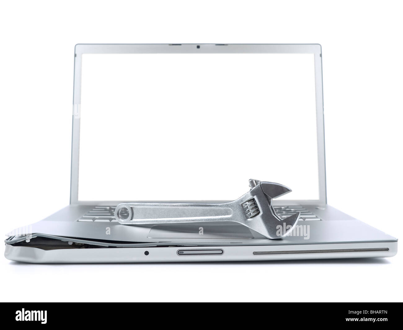 A spanner over a damaged laptop isolated over white background. Black ...
