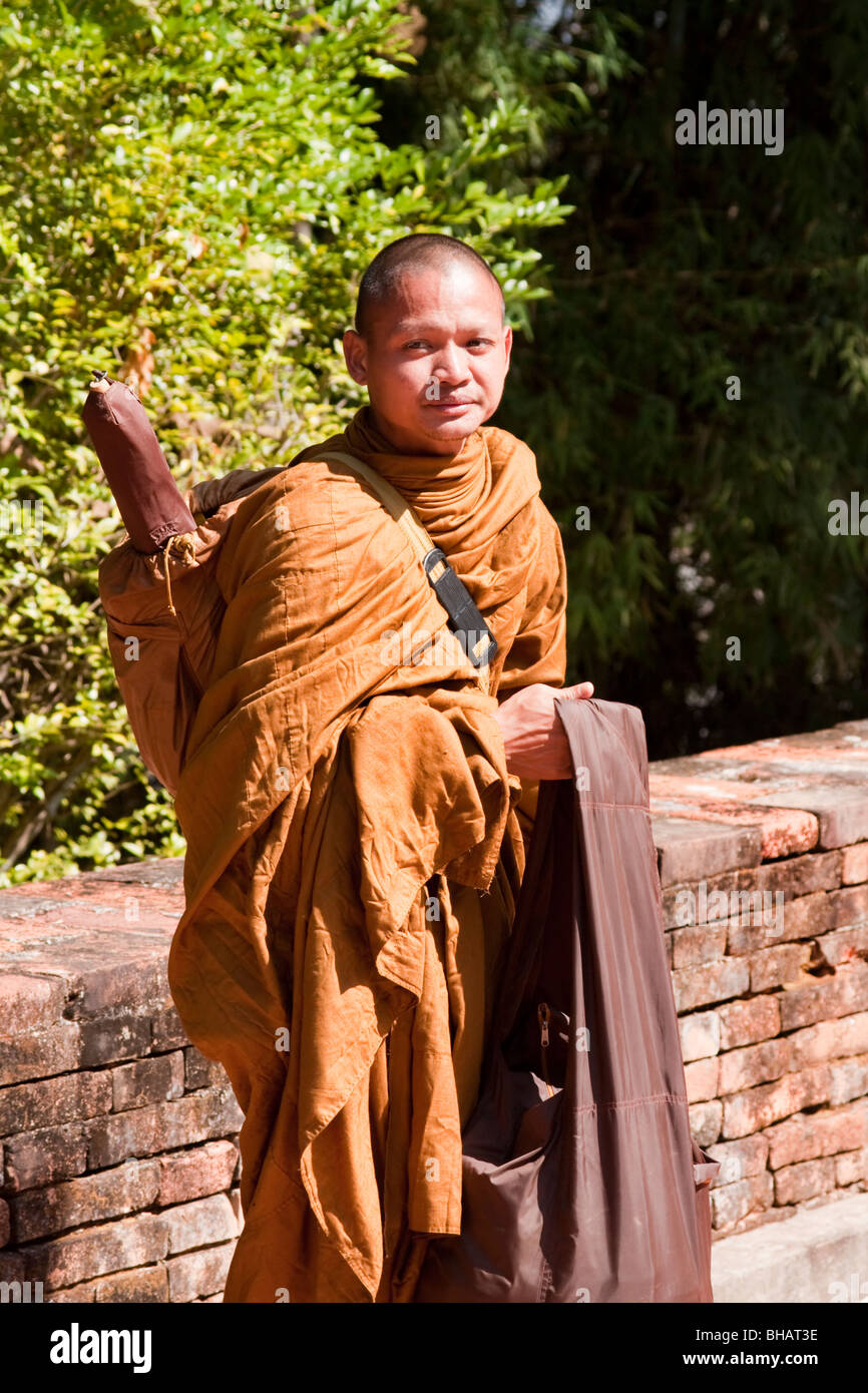 Thai Buddhist monk in traditional robe, standing in front of brick wall ...