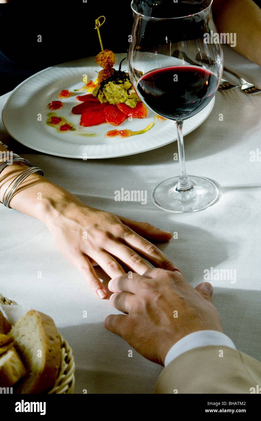 Closeup of couple's hands touching at dinner table Stock Photo - Alamy