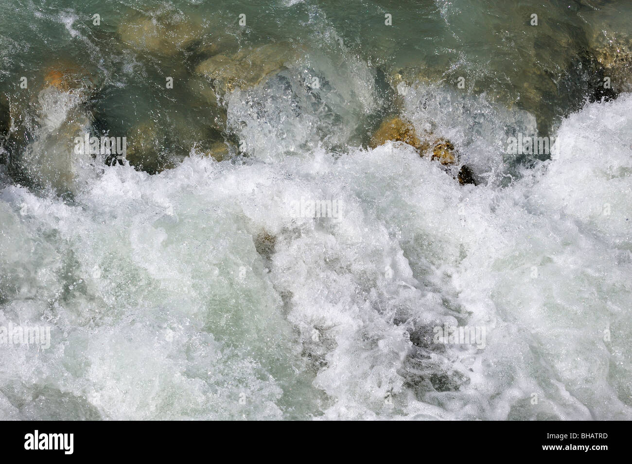 Glacial water flowing fast over boulders in alpine mountain stream ...
