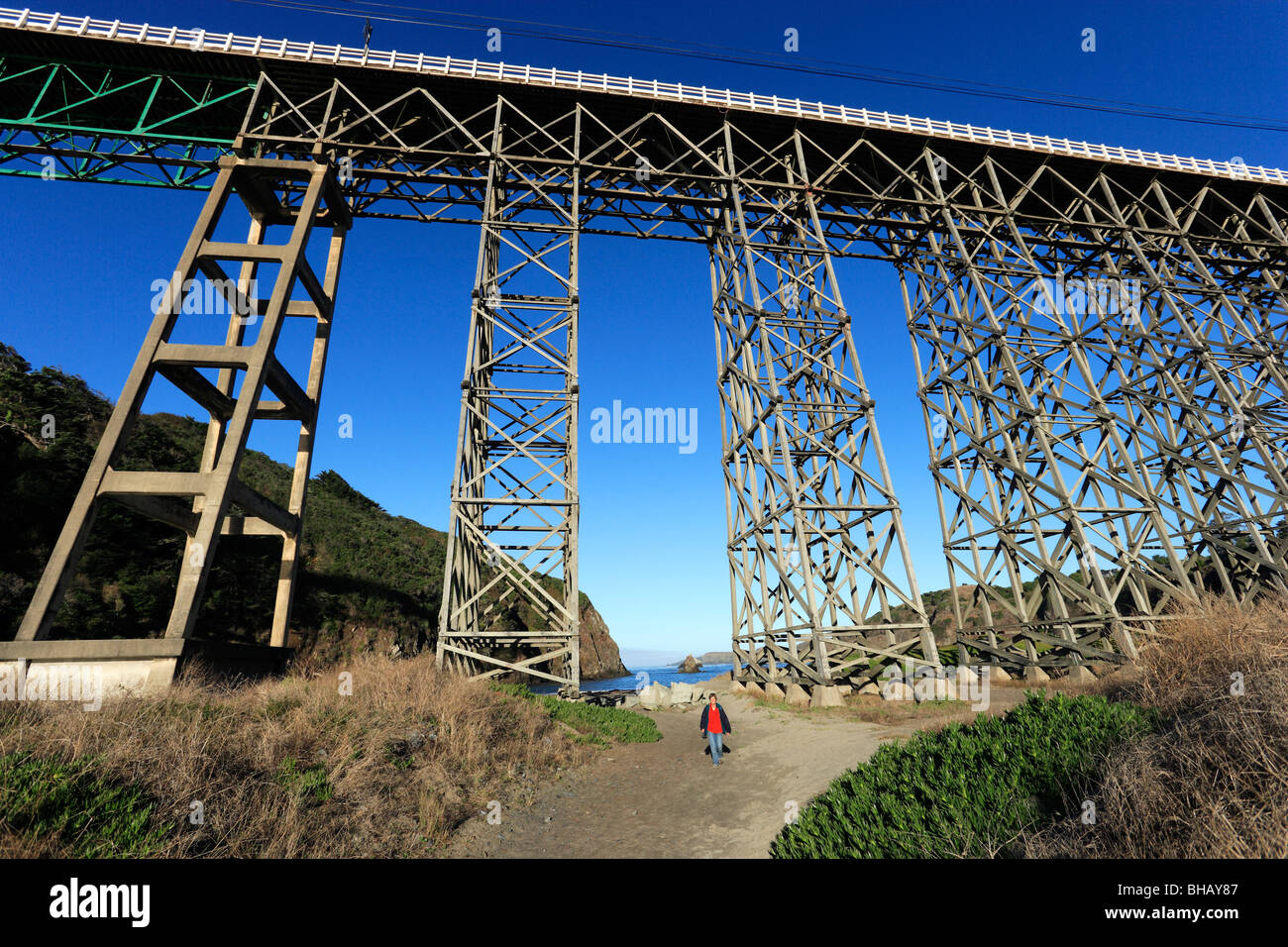 Woman walking beneath a deck truss bridge over Albion River on CA 1 ...
