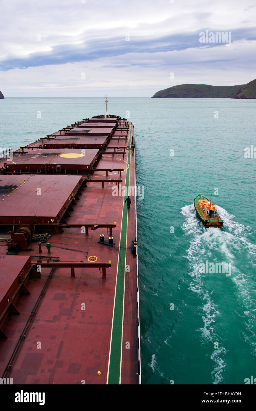 A large bulk carrier sails from port and the pilot boat waits alongside ...