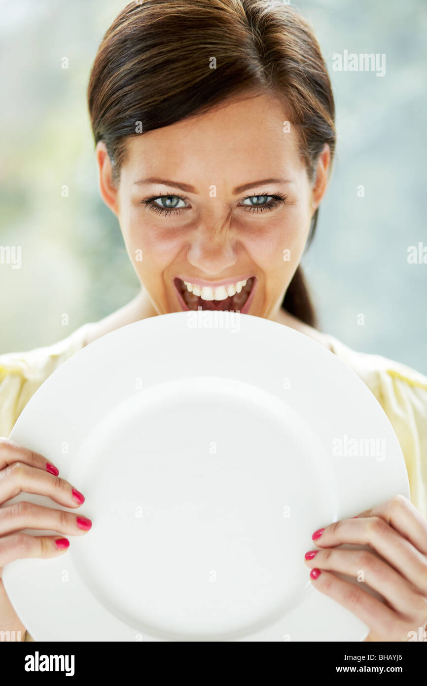 Girl biting plate Stock Photo - Alamy