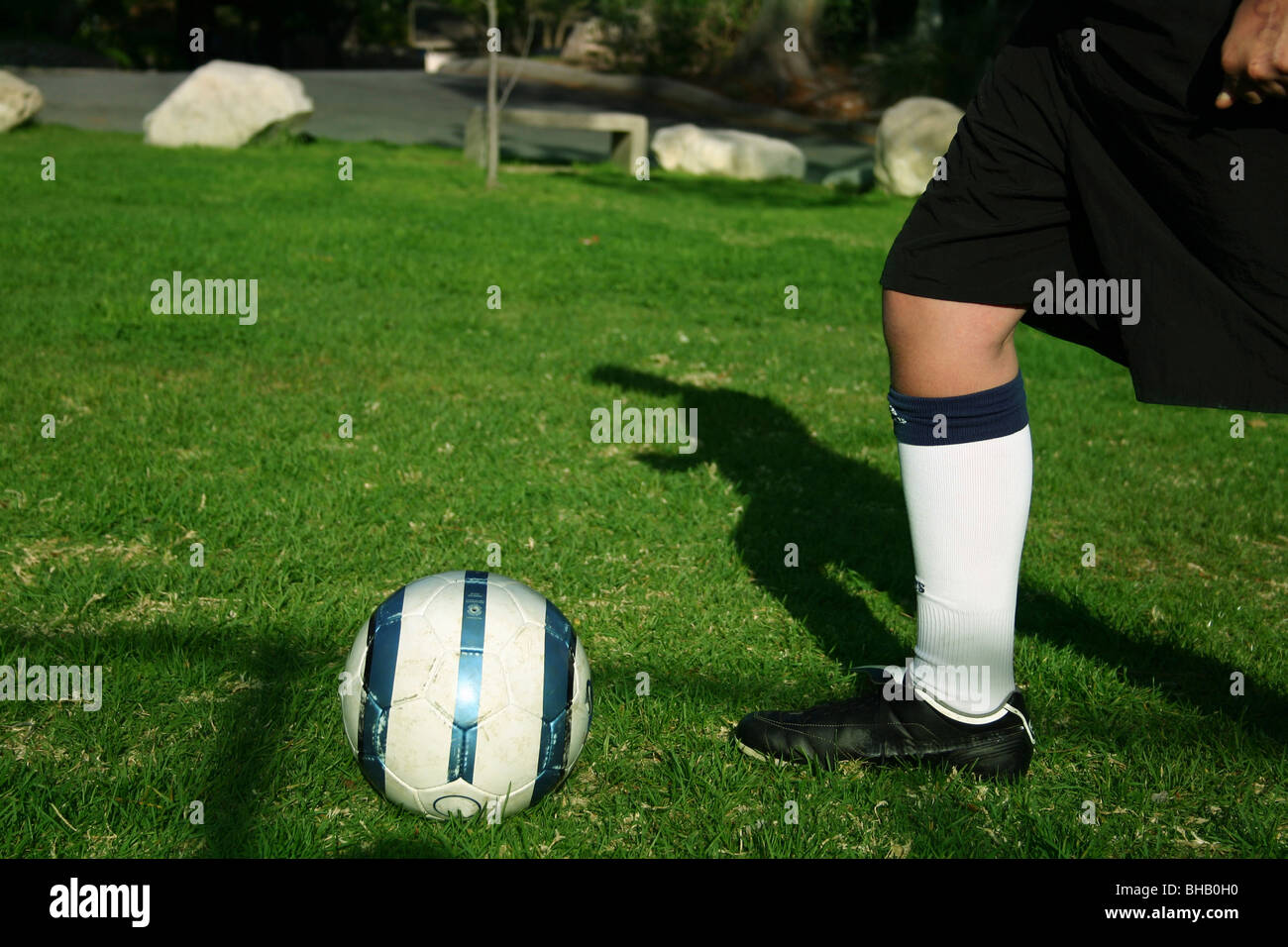 Footballer approaches football with shadow showing his shape in ...